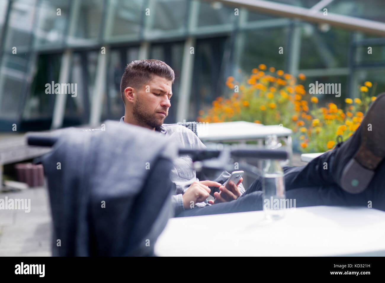 Man with feet on table texting on smartphone Stock Photo - Alamy