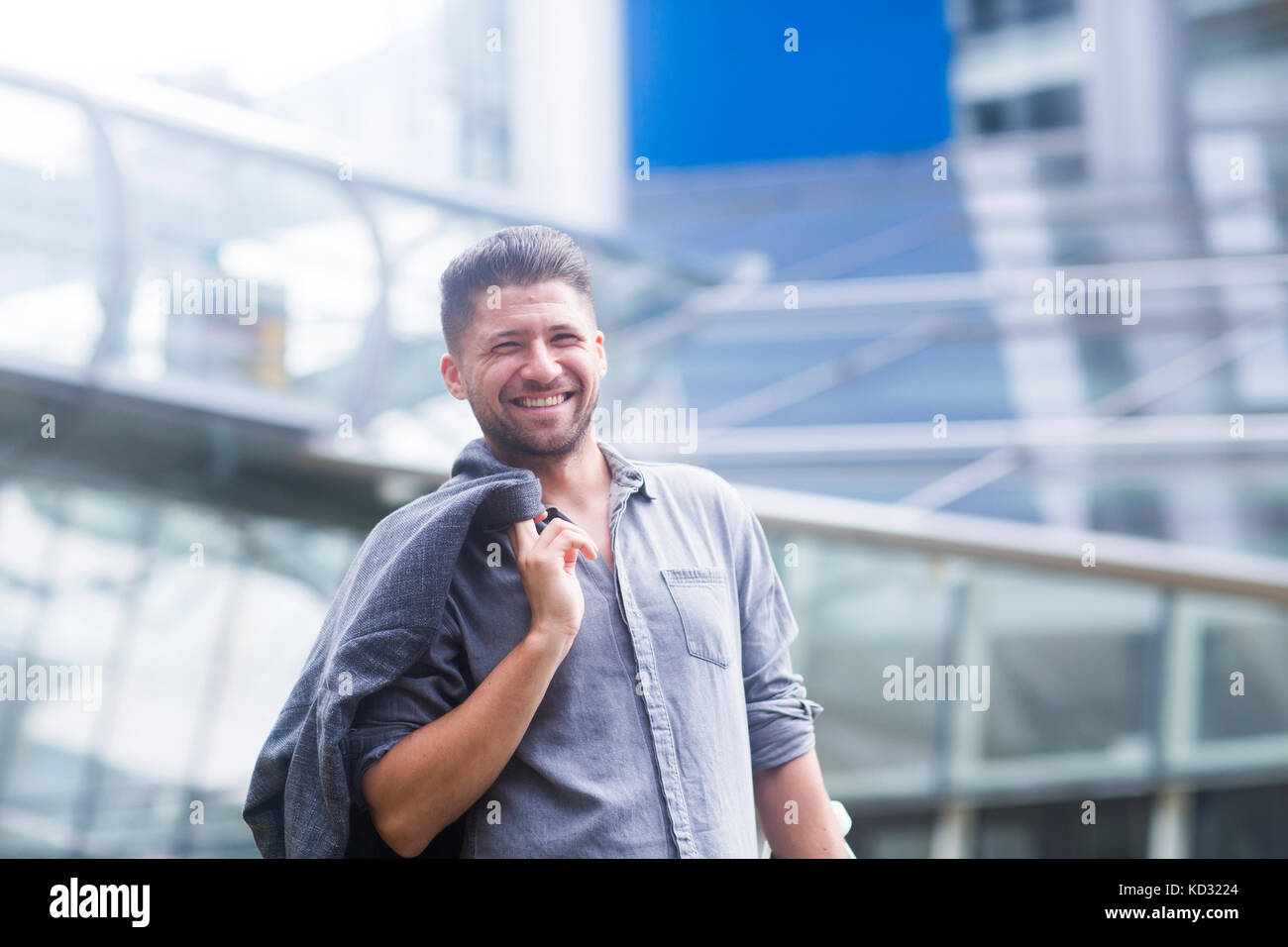 Portrait of man carrying jacket over shoulder looking at camera smiling ...