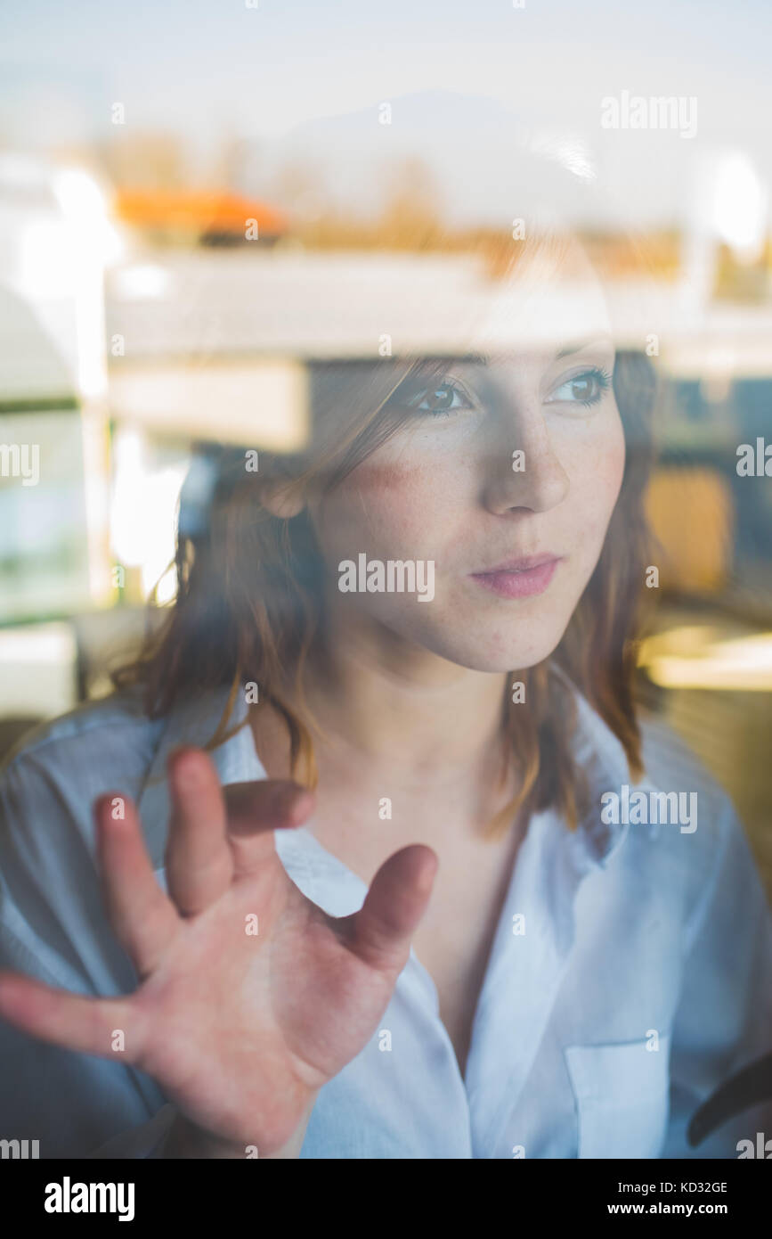 Portrait of young woman gazing out of window Stock Photo - Alamy