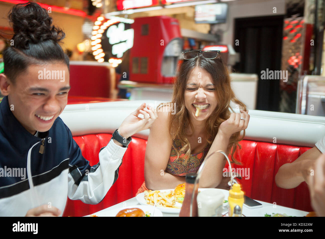 Three young friends sitting in diner, laughing Stock Photo - Alamy