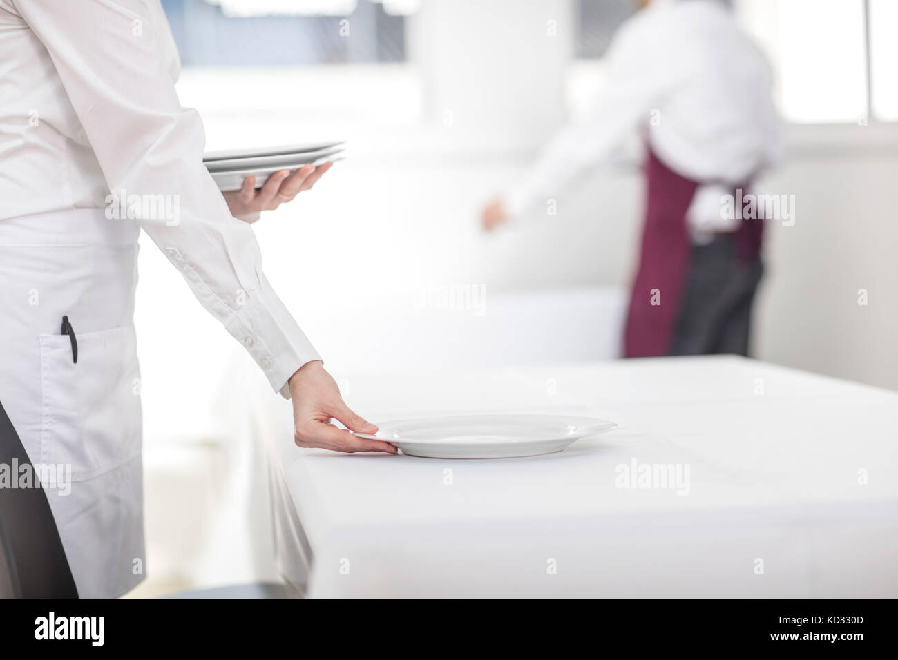 Waitress laying table in restaurant, mid section Stock Photo - Alamy