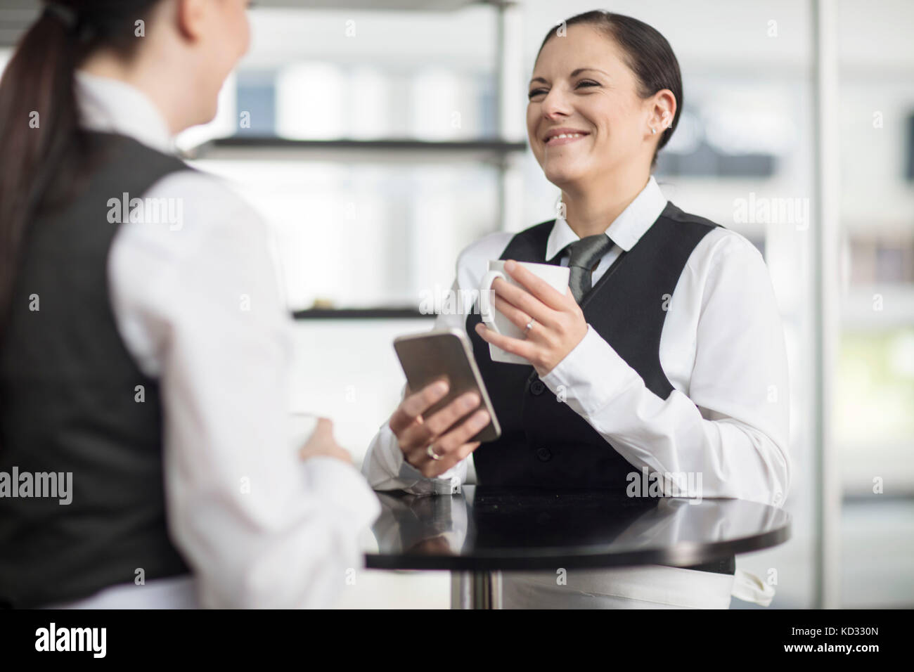 Two waitresses in restaurant, taking a break, talking Stock Photo - Alamy
