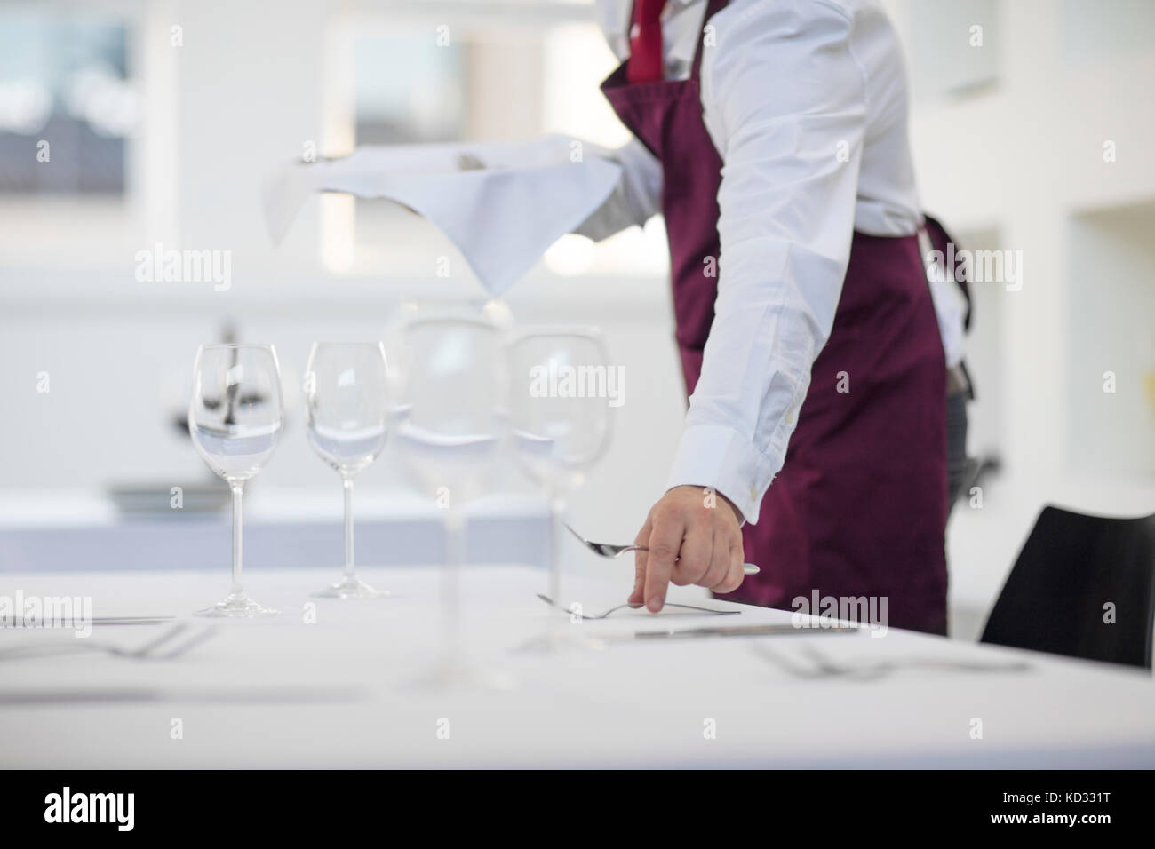 Waiter laying table in restaurant, mid section Stock Photo - Alamy