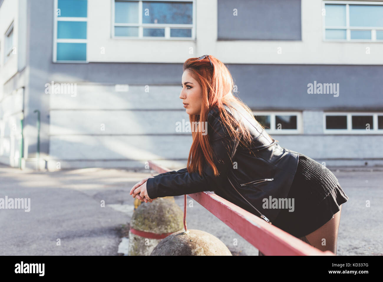 Portrait of red haired woman leaning against railing looking away Stock ...