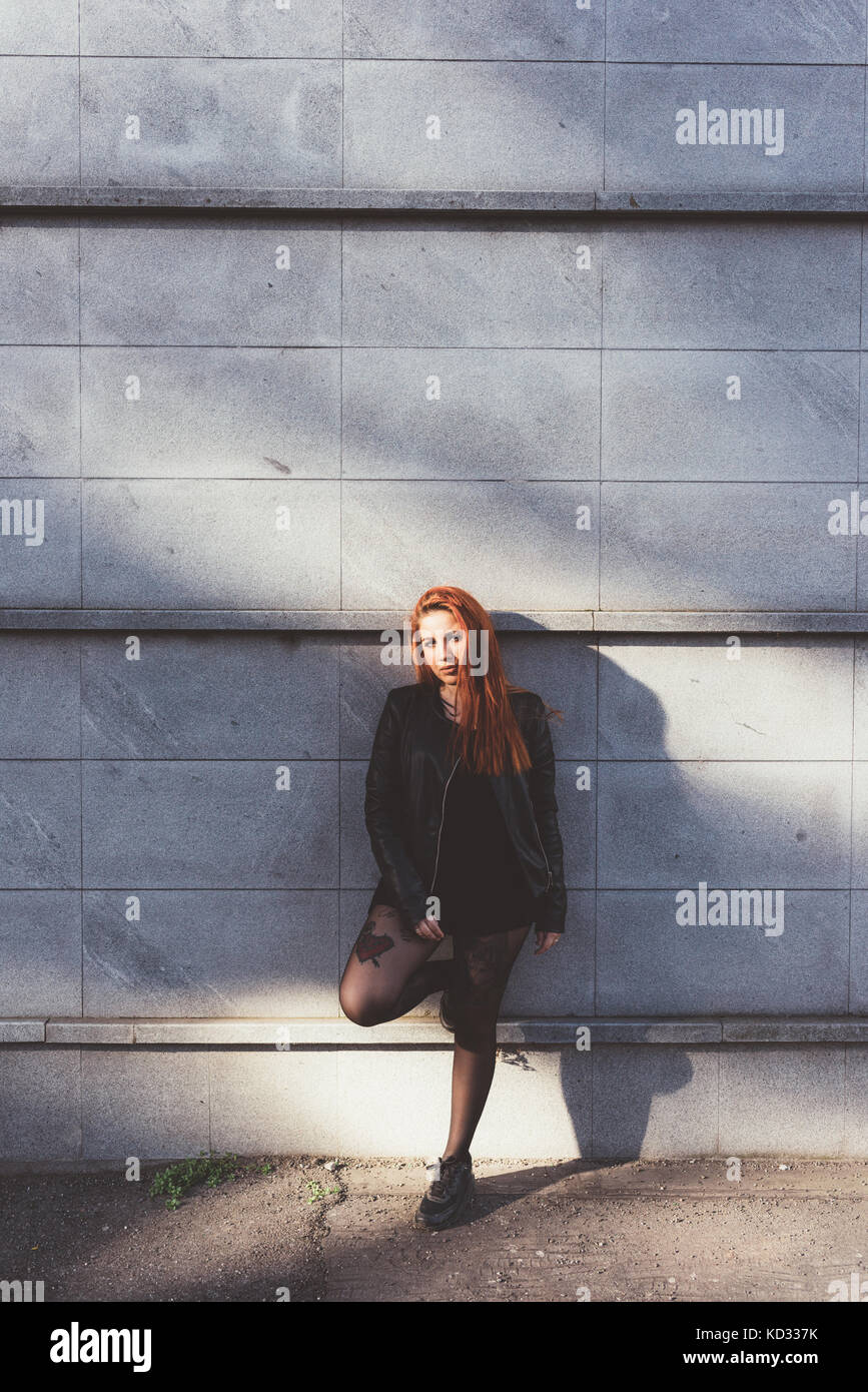 Portrait of red haired woman leaning against wall Stock Photo - Alamy