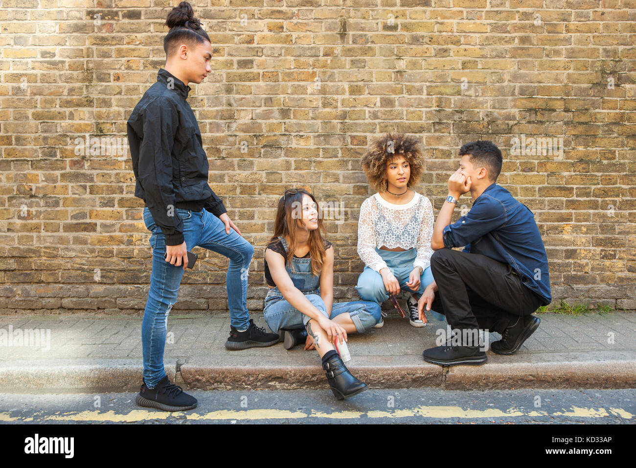 Four friends hanging out in street, talking Stock Photo - Alamy
