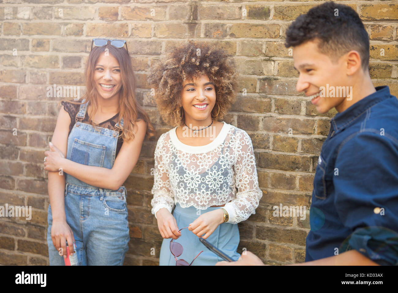 Three friends standing together in street, laughing Stock Photo - Alamy
