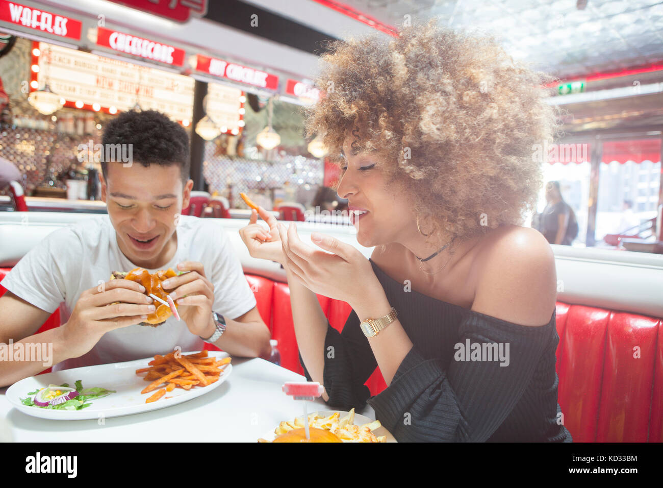 Young couple, sitting in diner, eating meal Stock Photo - Alamy