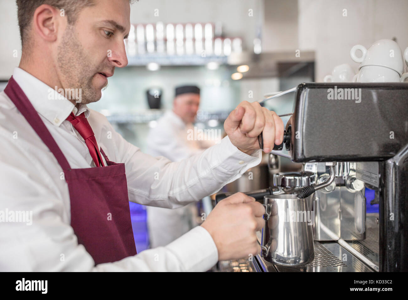 Waiter in restaurant using coffee machine Stock Photo - Alamy