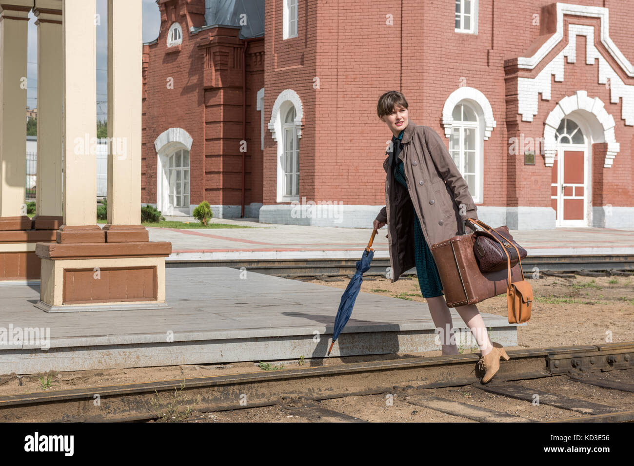 Young woman walks on rails at a train station with luggage Stock Photo ...