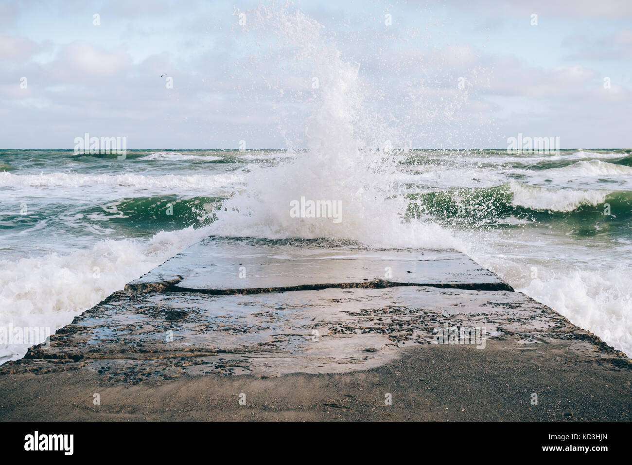 Sea wave breaking on the pier. View from the beach Stock Photo - Alamy