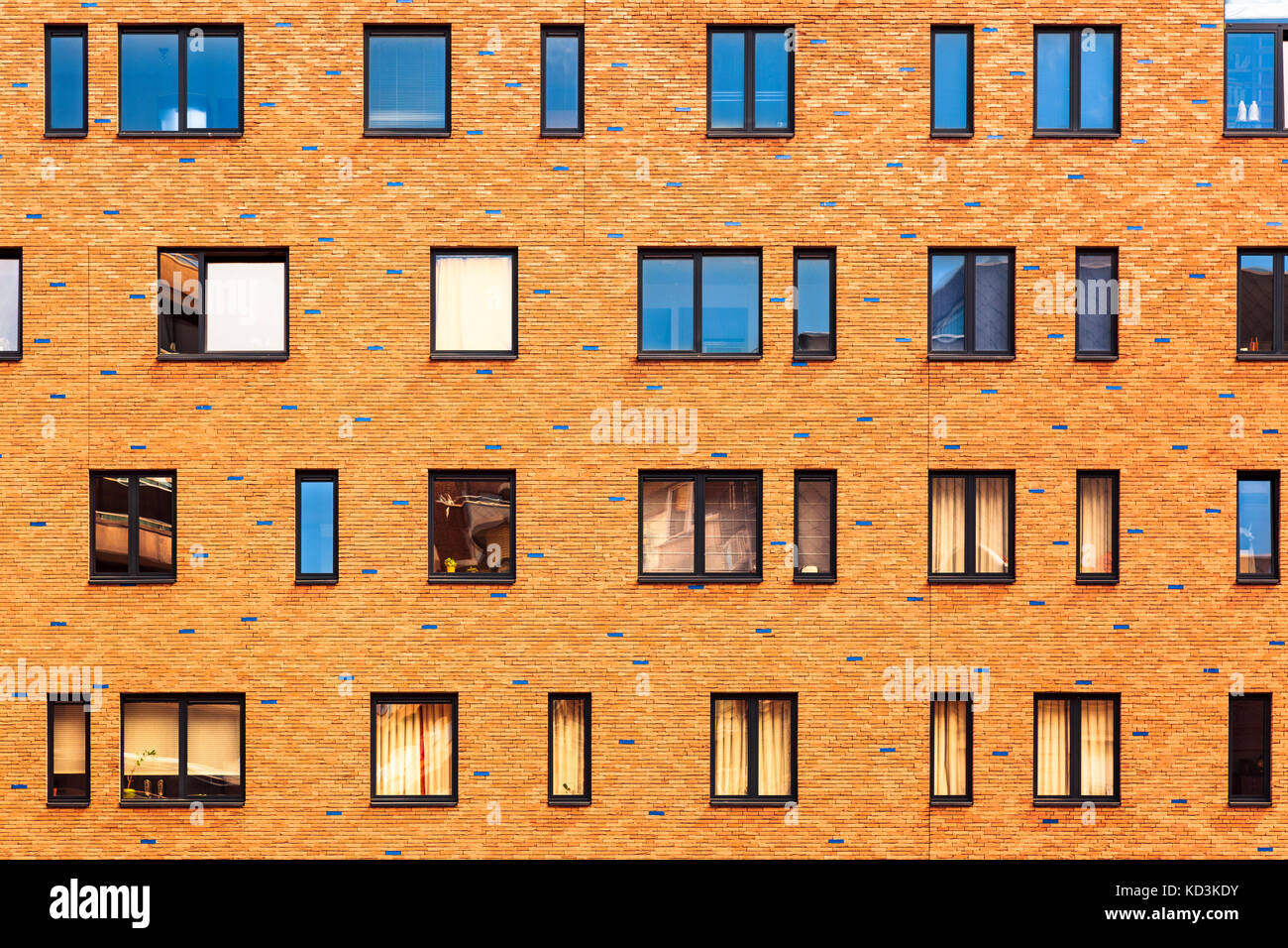 Facade of a residential orange brick building with lots of windows of ...