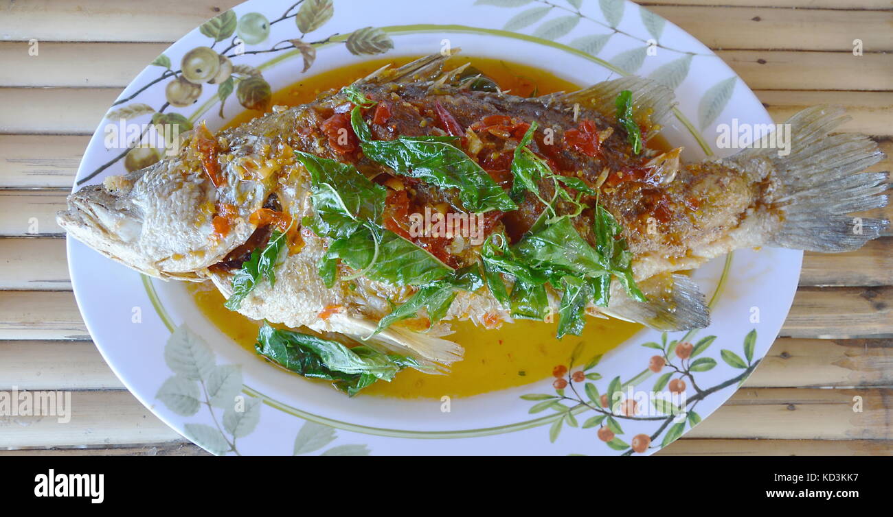 fried bass fish dressing with chili sauce on plate Stock Photo - Alamy