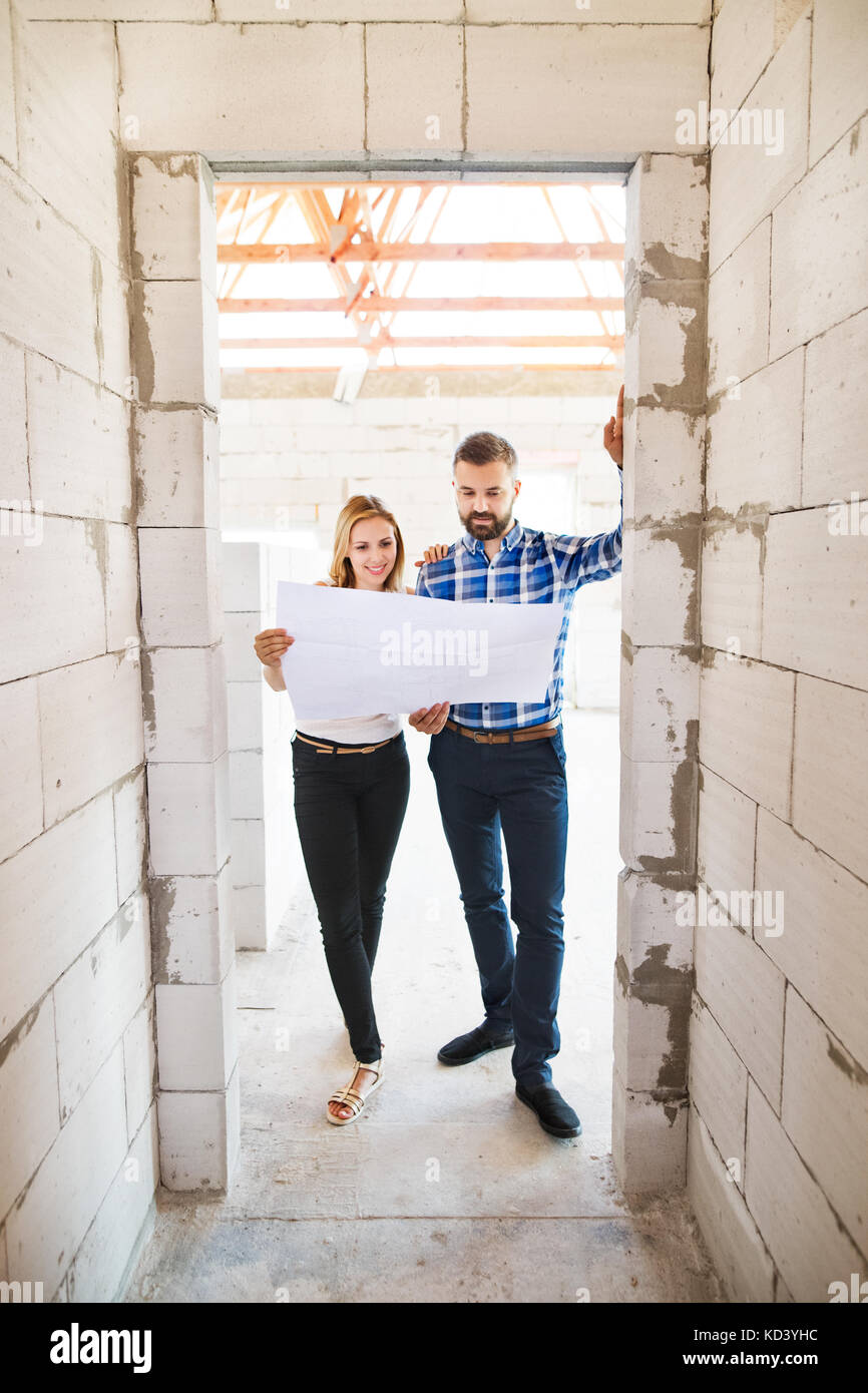 Young couple or architects or civil engineers looking at plans of the ...