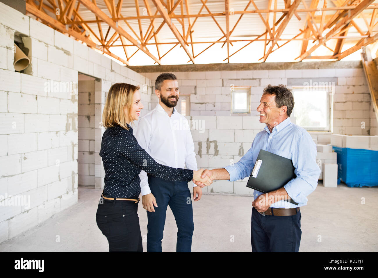 Young couple with architect or civil engineer looking at plans of their ...