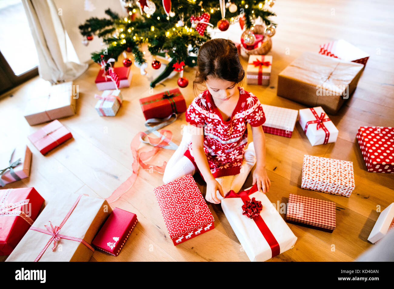 Beautiful little girl under the Christmas tree opening presents Stock ...