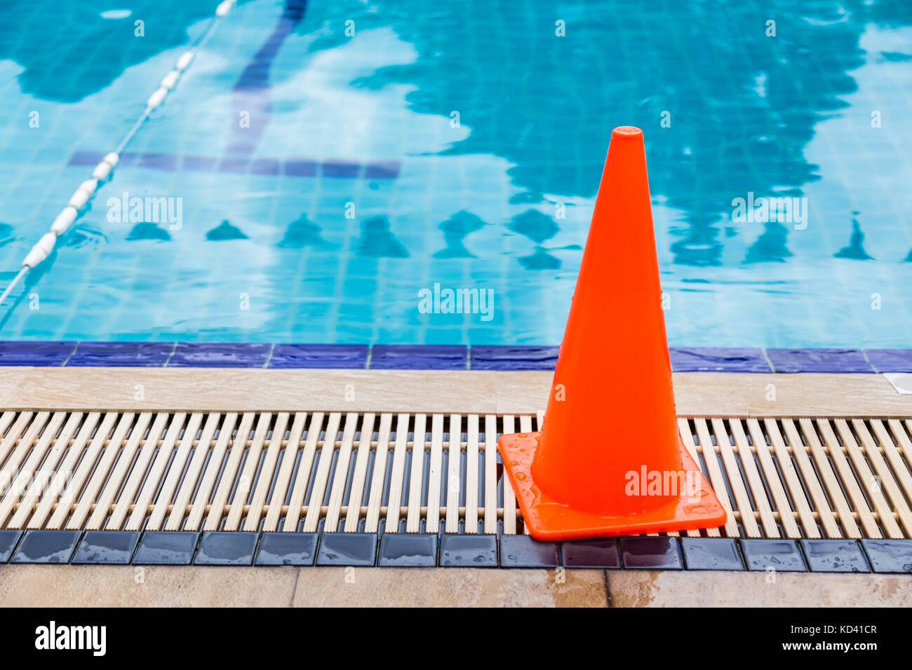 wet bright orange cone placed by the swimming pool side as safety ...