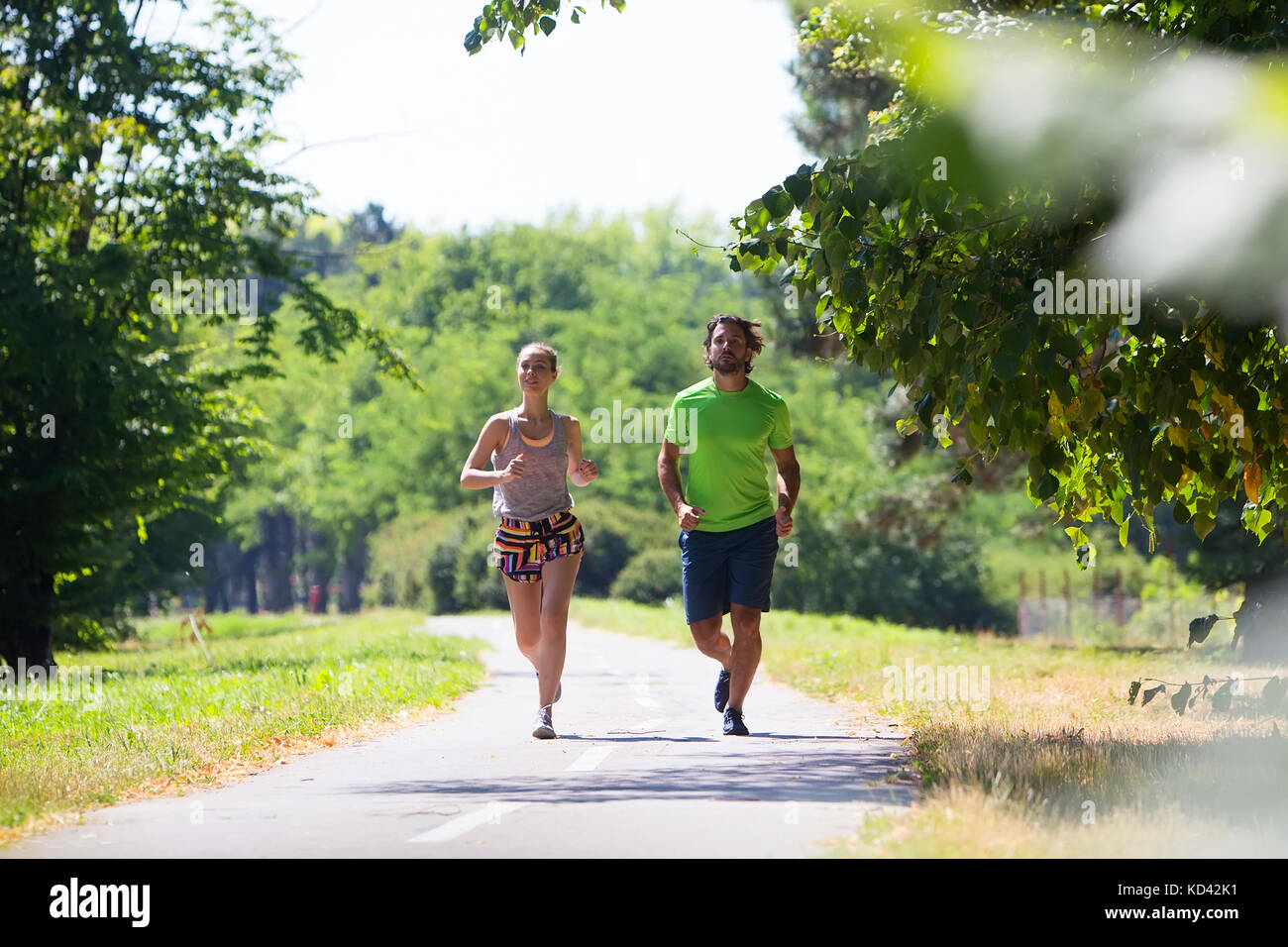 Healthy, fit and sportive couple running in park at summer morning ...