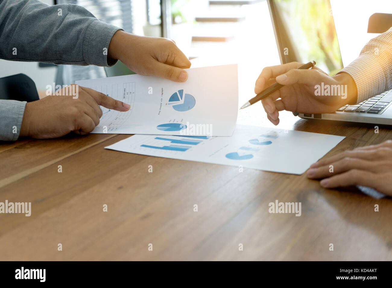 Two businessman working use computer and analysis paper graph on wood ...