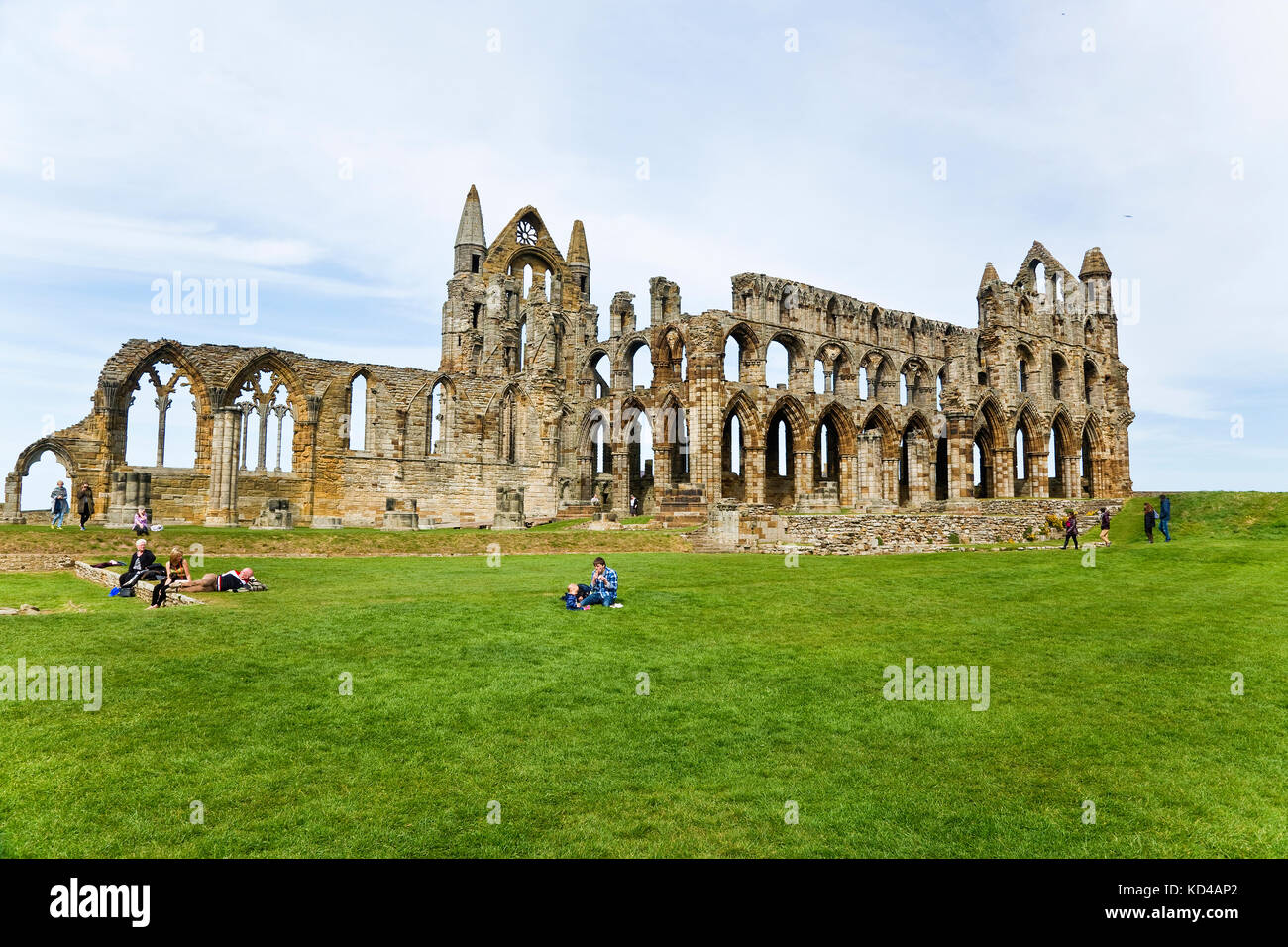 View of Abbey ruins on top of cliffs above Whitby Town with people ...