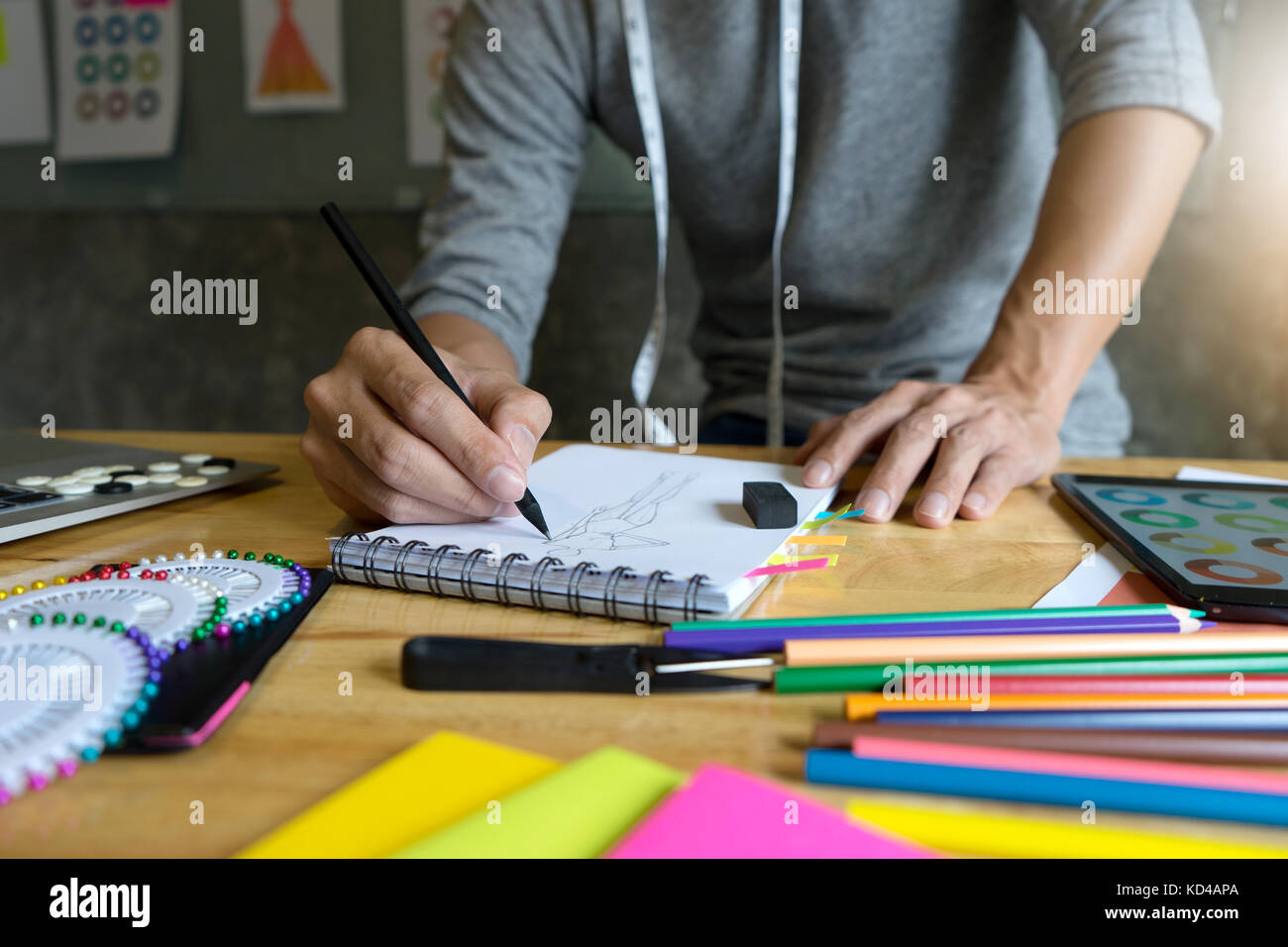 young male fashion designer work with fabric cloth on the wood table ...