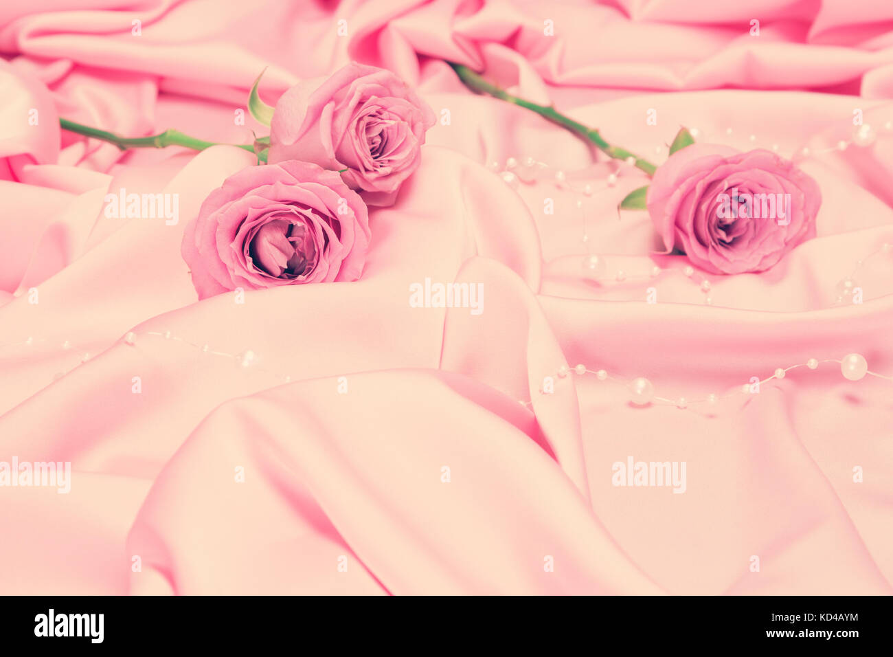 Rose flowers on pink satin fabric with bead strand. Romantic vintage ...