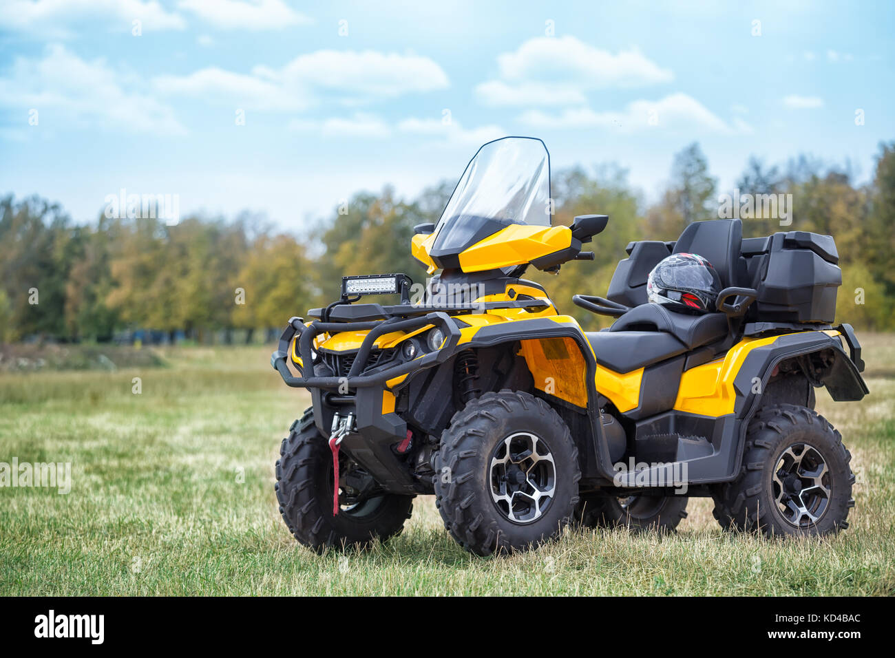 Yellow ATV and helmet on green field grass Stock Photo - Alamy