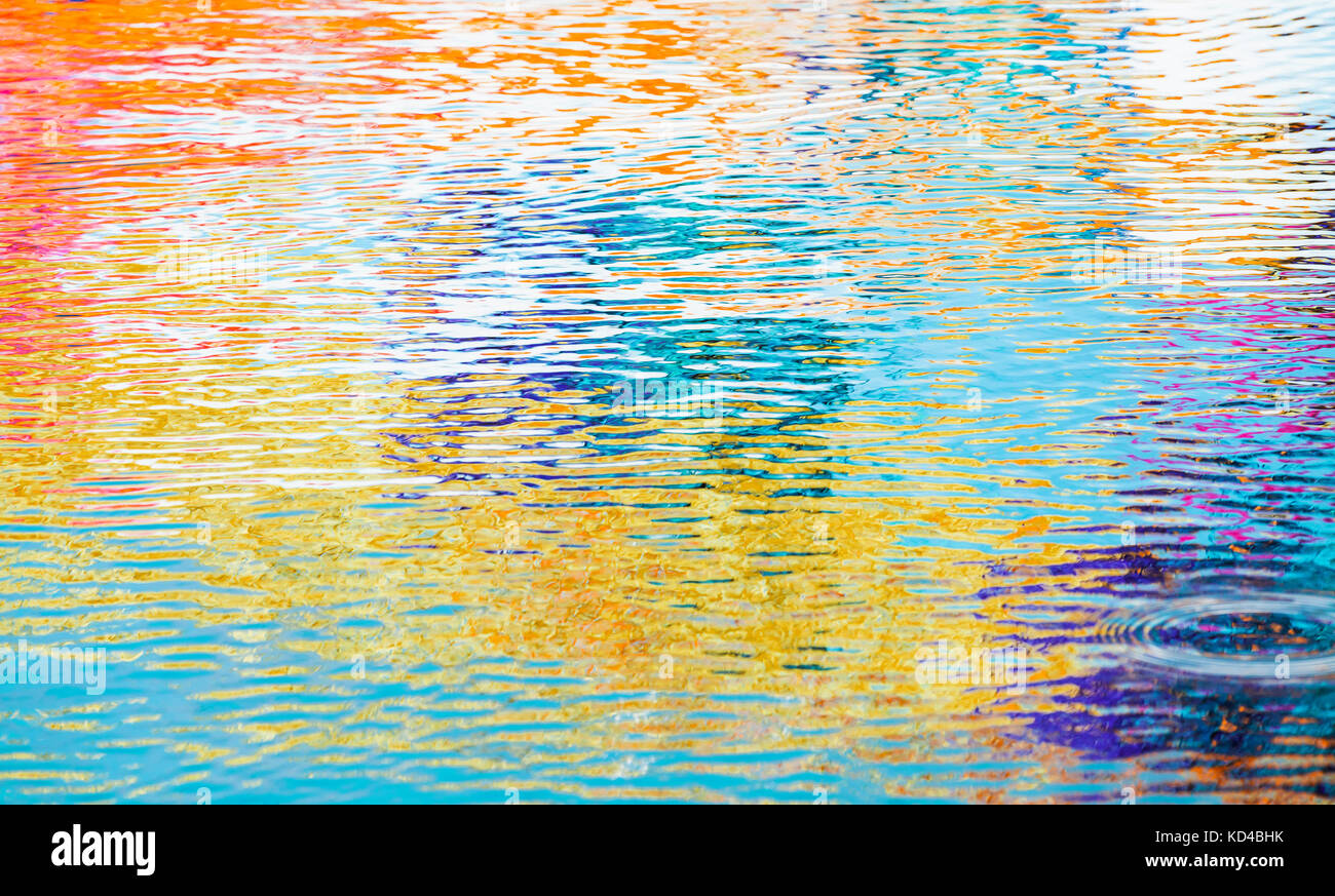 Rippled water surface texture with bright colorful reflections ...