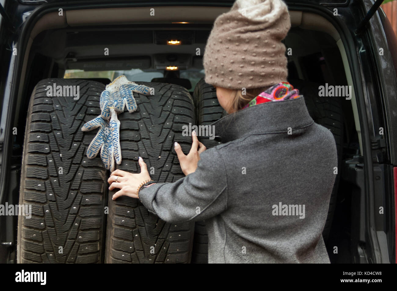 Young female loading heavy winter tyres in open car boot Stock Photo ...