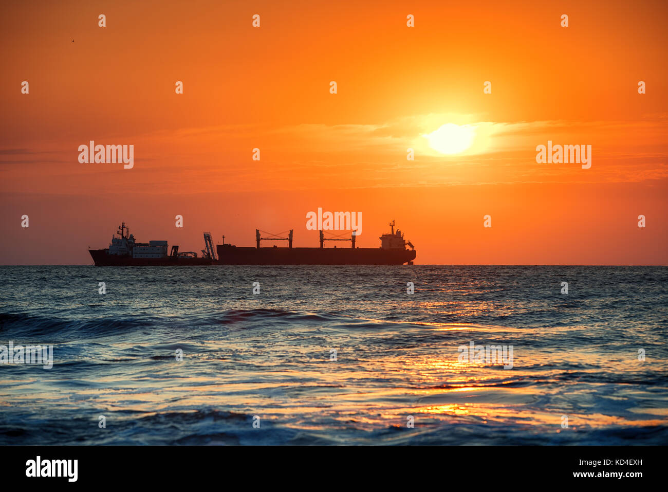Sun setting at the sea with sailing cargo ship, scenic view Stock Photo ...