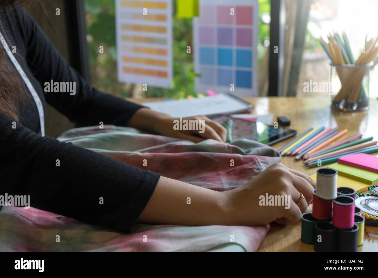 young fashion designer work with fabric cloth on the wood table near ...