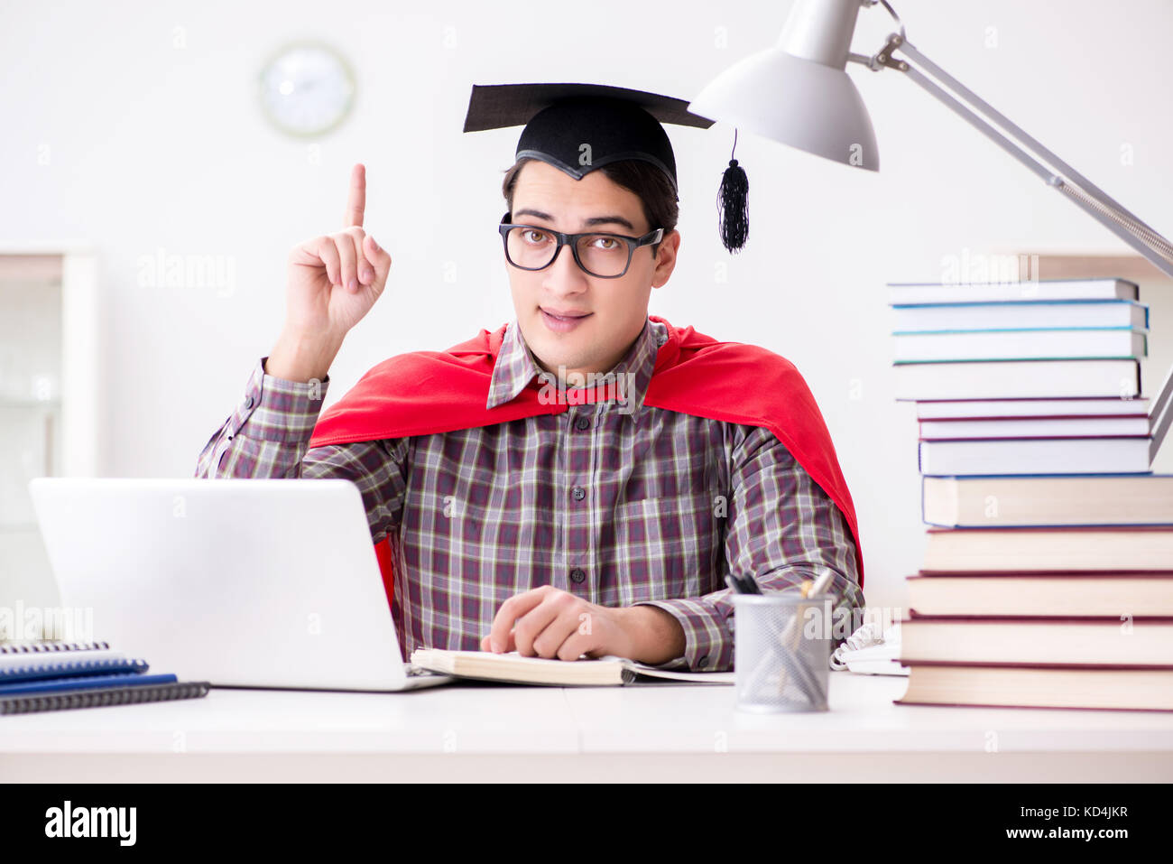 Super hero student wearing a mortarboard studying for exams Stock Photo ...