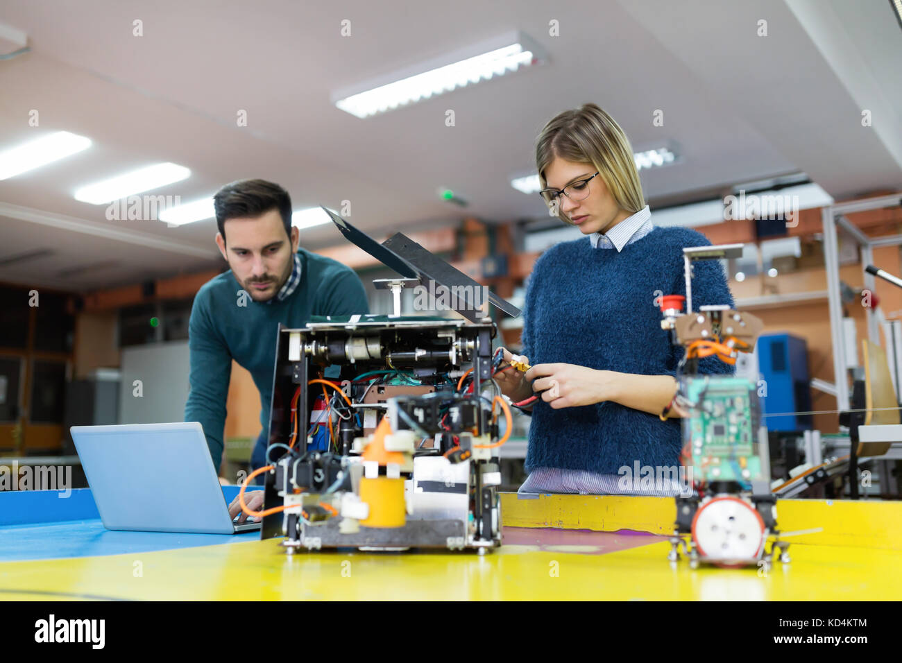 Young students of robotics preparing robot for testing Stock Photo - Alamy