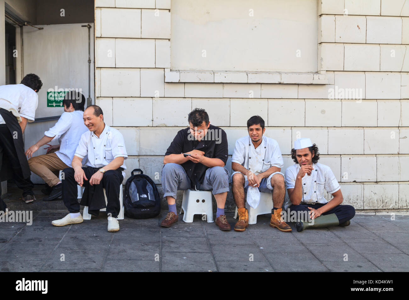 Chefs in white uniform taking a cigarette break and sitting outside the ...