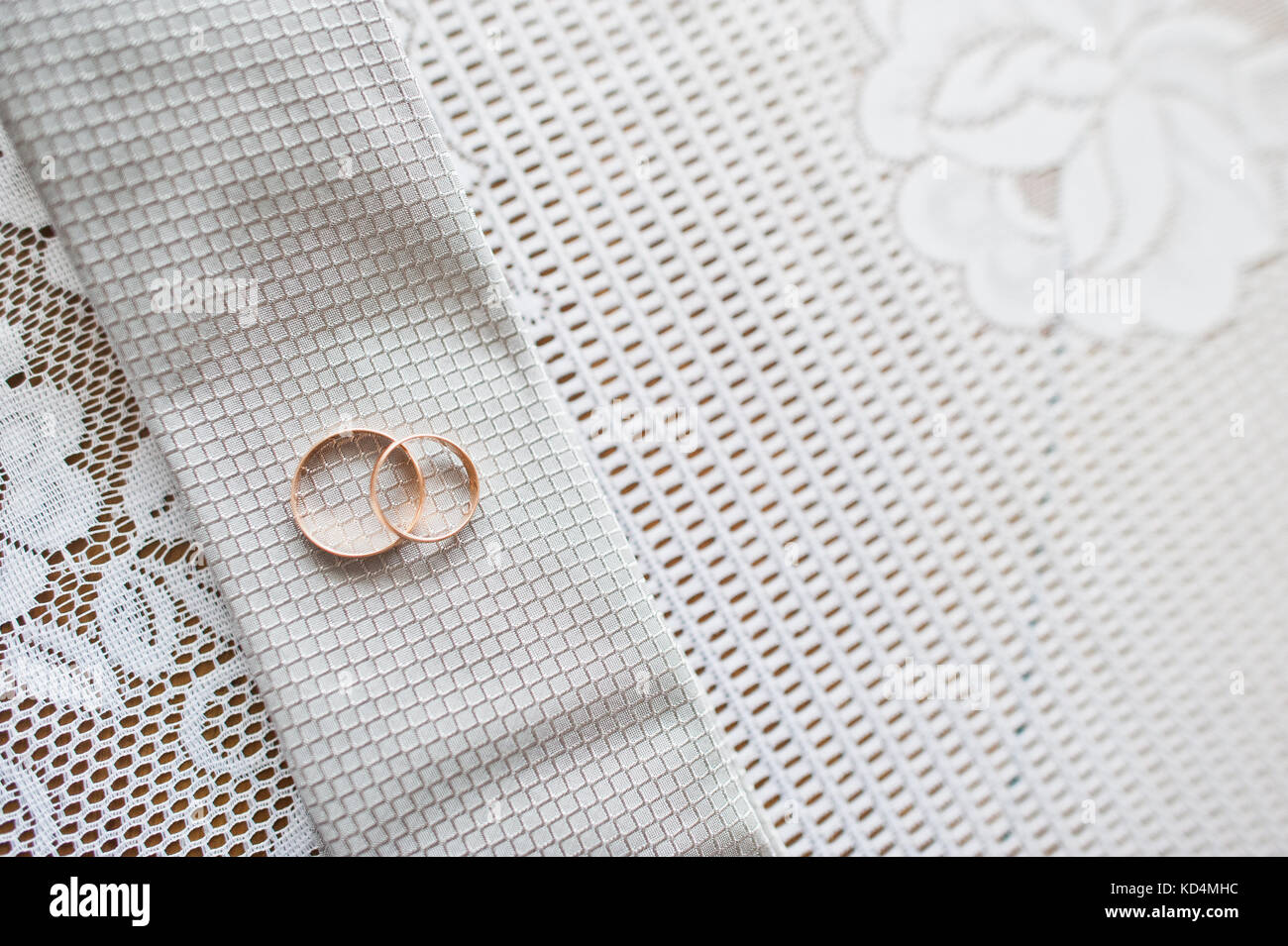 Close-up photo of white tie laying on the table with golden wedding ...