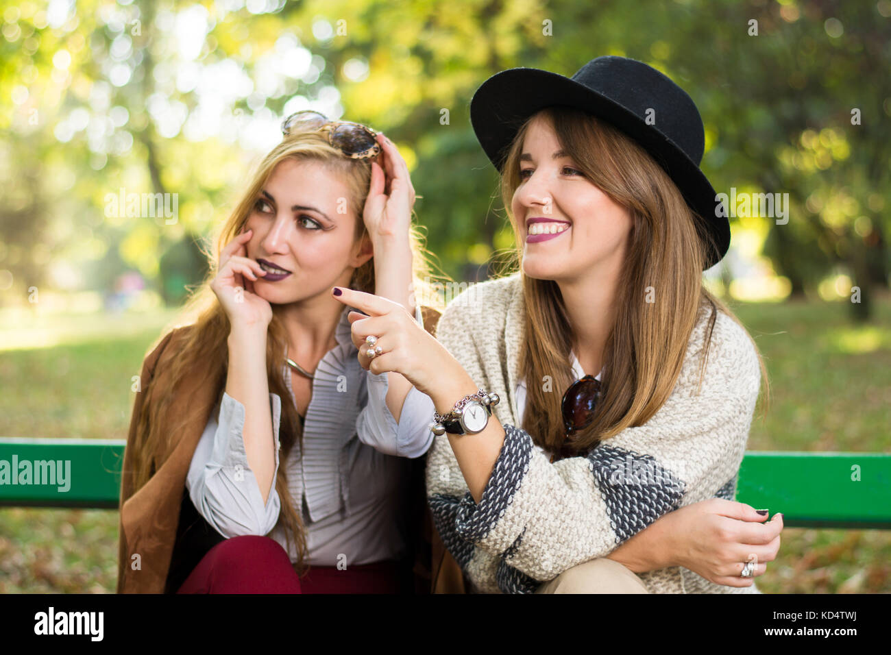 Female friends gossiping on a park bench Stock Photo - Alamy