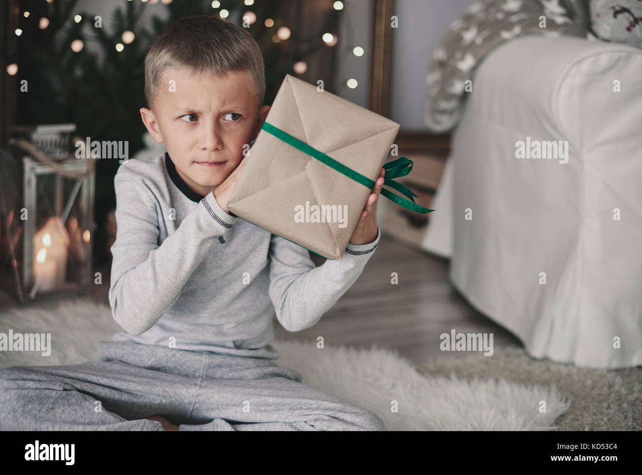 Boy shaking a wrapped present Stock Photo - Alamy