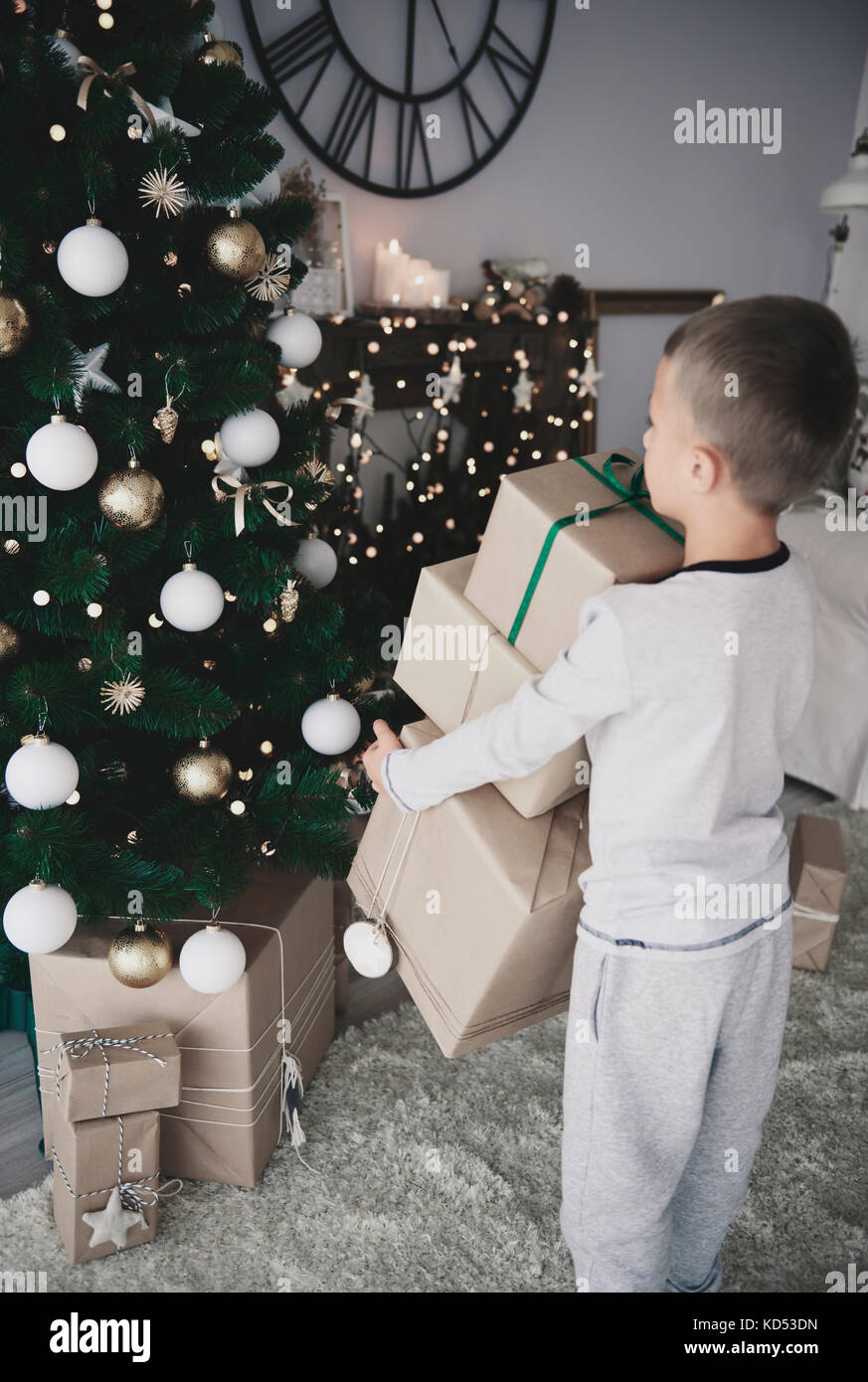 Child putting gifts under a christmas tree Stock Photo - Alamy