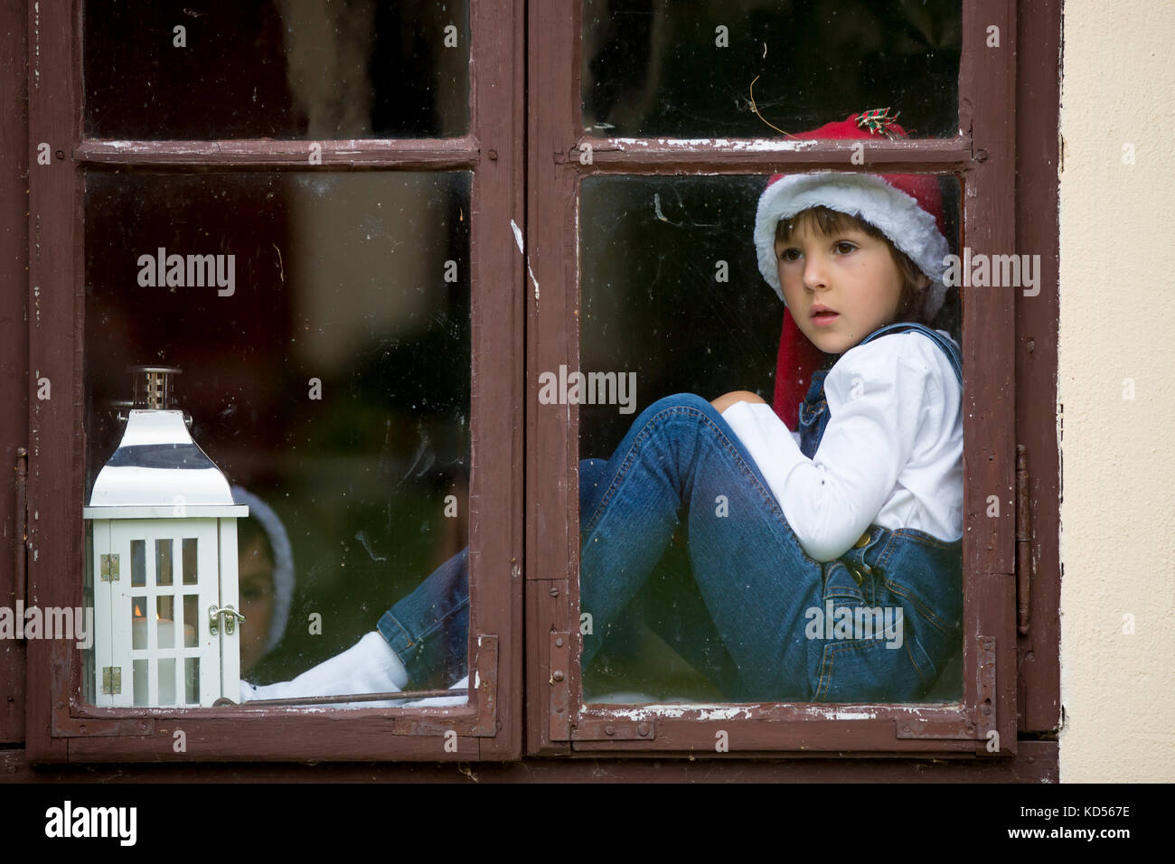 Two cute boys, brothers, looking through a window, waiting impatiently ...