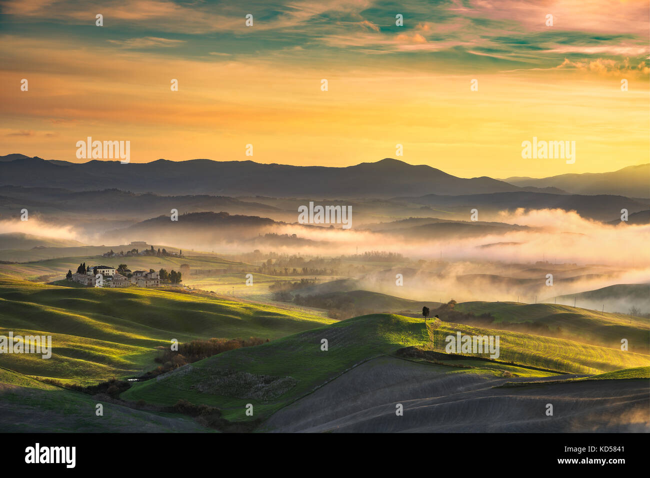 Volterra foggy panorama, rolling hills and green fields on sunset ...