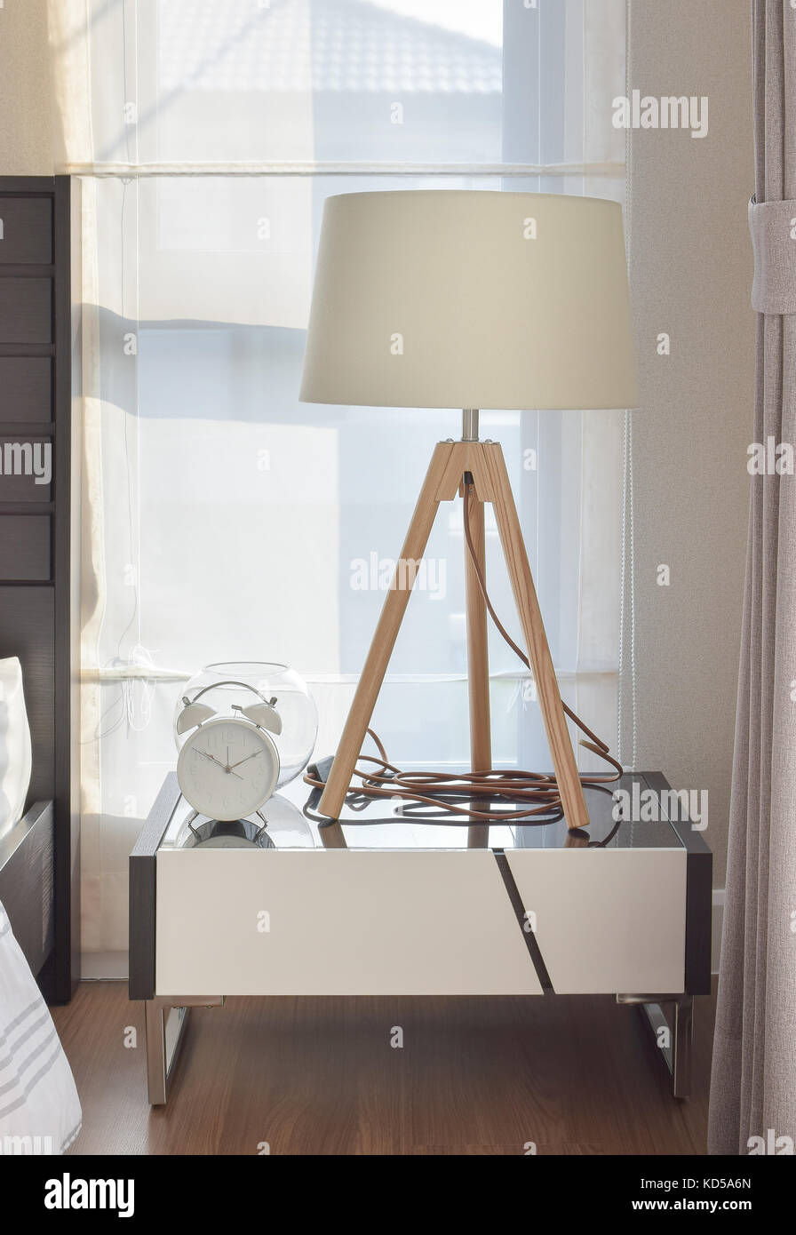 modern bedroom interior with wooden lamp and alarm clock on bedside ...