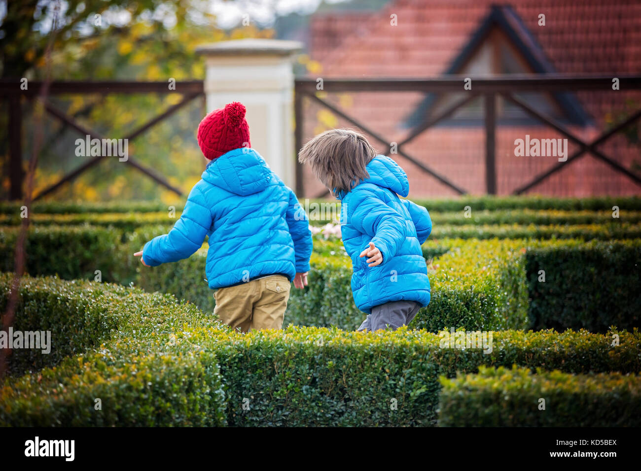 Two children, boys, running happily in labyrinth in the park while ...