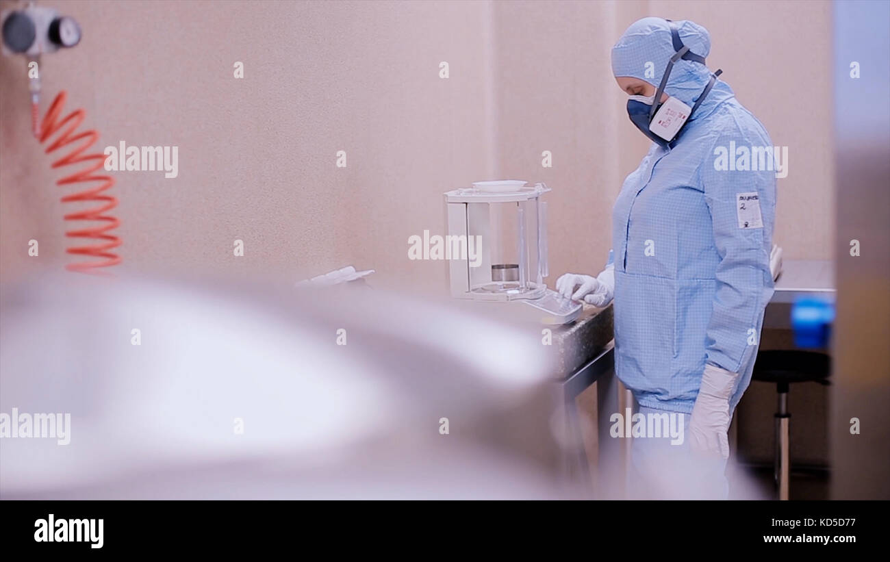 Female scientist in a protective suit working with specimen bottles in ...