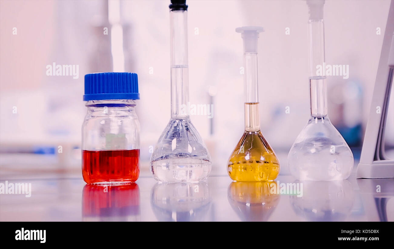 Laboratory flasks and beakers with liquids of different colors on lab ...