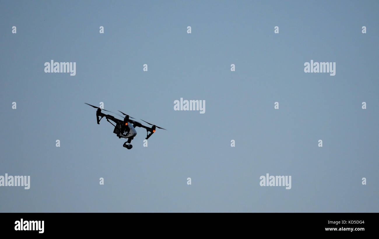 Black drone quadcopter with camera flying over blue sky. Black drone in ...