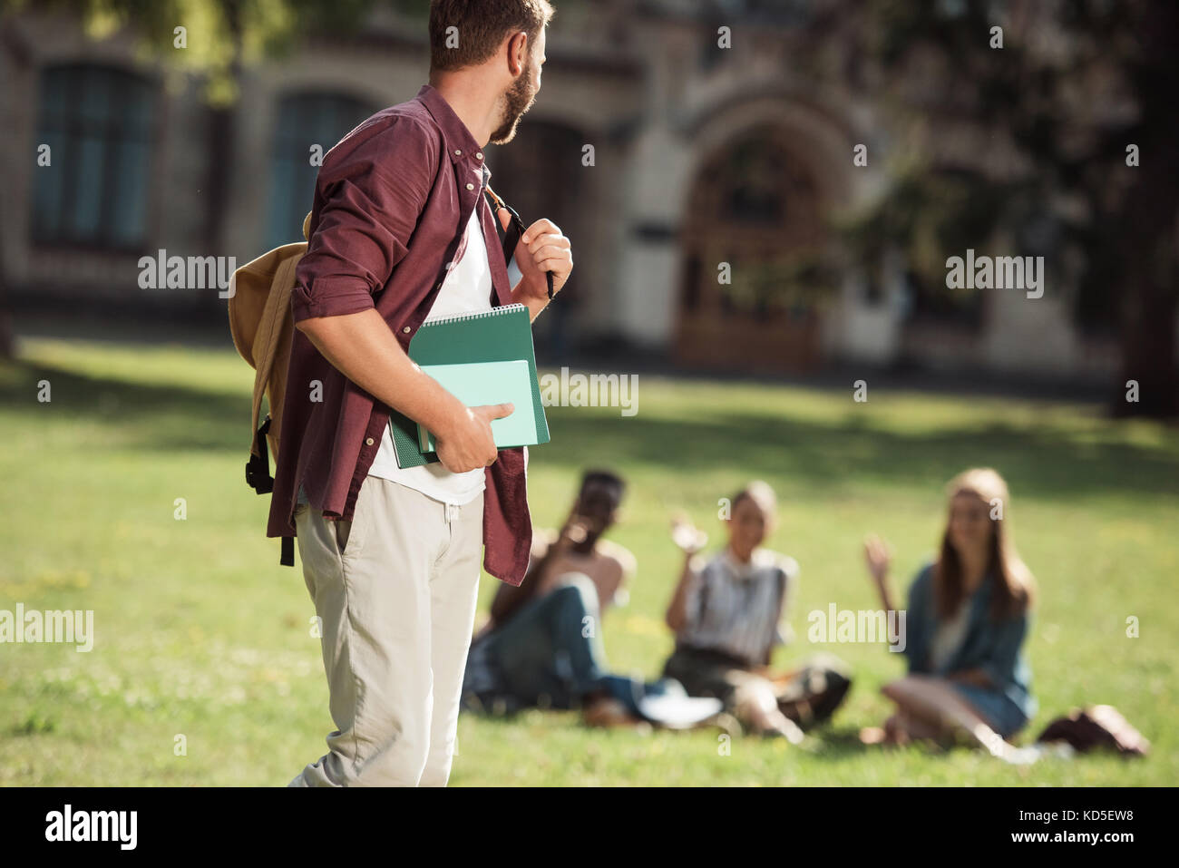 student with books looking at friends Stock Photo - Alamy