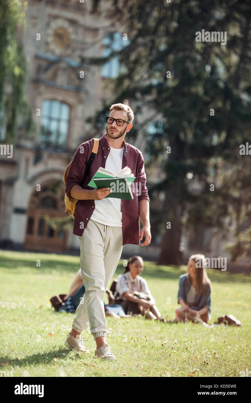 student walking with and reading book Stock Photo - Alamy