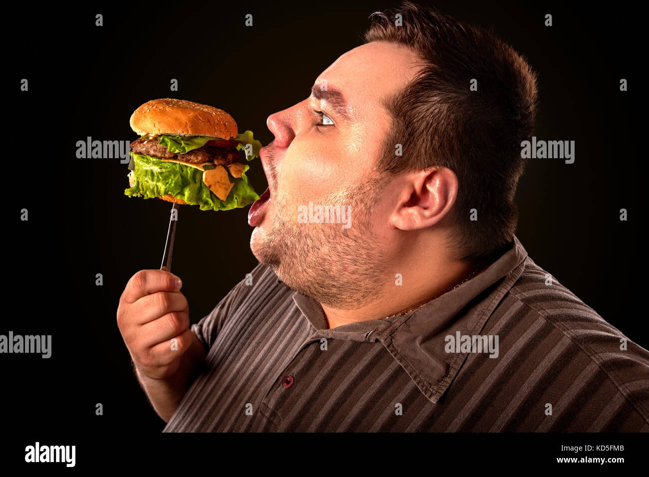 Fat man eating fast food hamberger. Breakfast for overweight person ...
