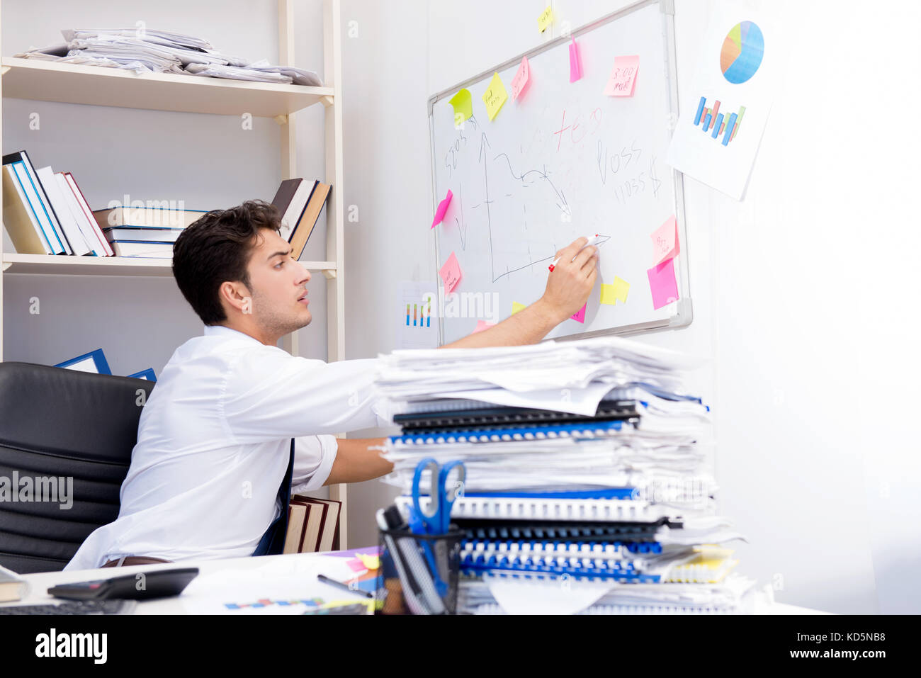 Businessman working in the office with piles of books and papers doing ...