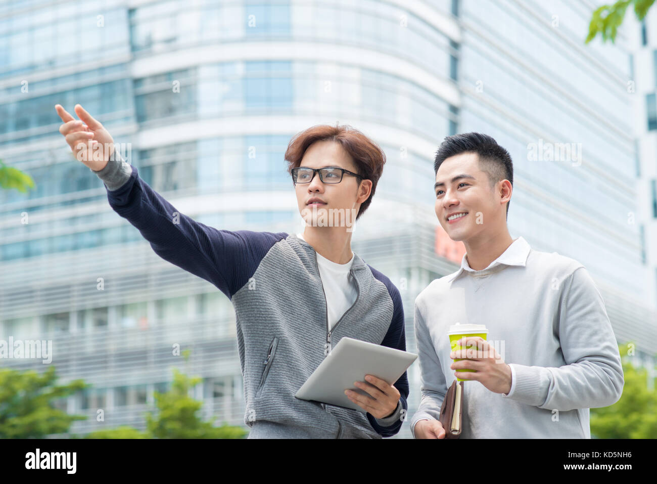 Two smiling male work coworkers outdoors talking together over a ...